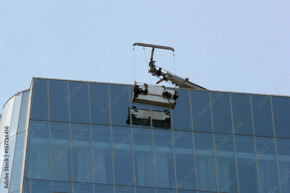 Window washing platform suspended on glass facade of a skyscraper ...