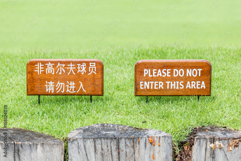 No entry wooden sign in English and Chinese placed on green grass and ...