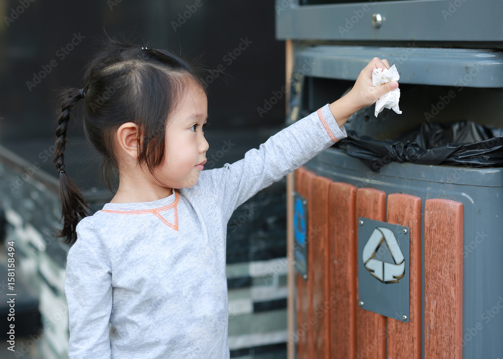 Cute little girl putting waste in the bin outdoor. Stock Photo | Adobe ...