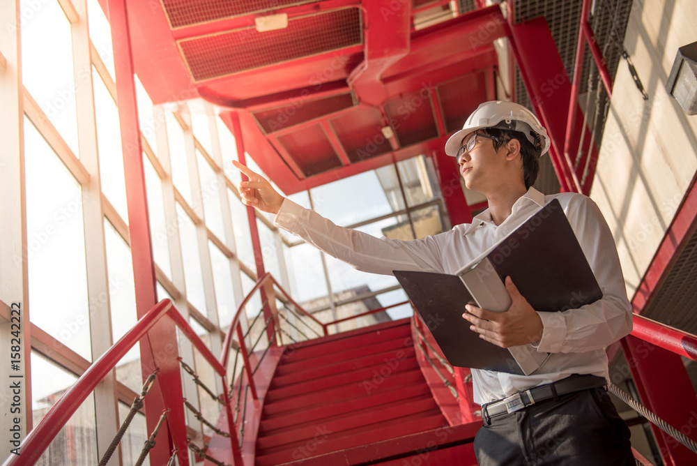 Young Asian Engineer or Architect holding files while wearing personal ...