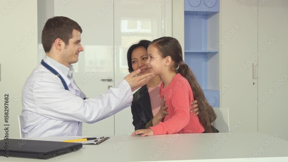 Young male doctor checking up little girl at the office. Attractive ...