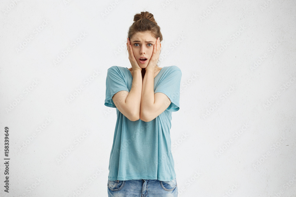 Emotional worried young female in casual clothes holding hands on her ...