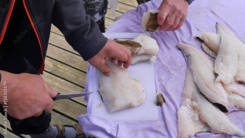 Fish fillet cutting on the street market. Male hands are preparing fish ...