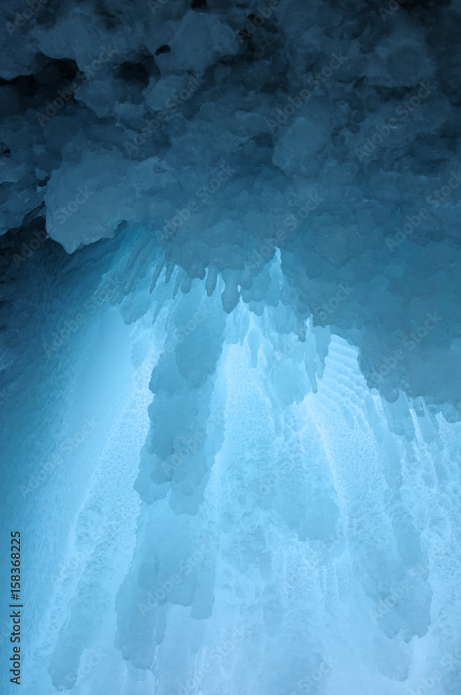 view from ice cave. frozen, crystal clear water drops like stalactites ...