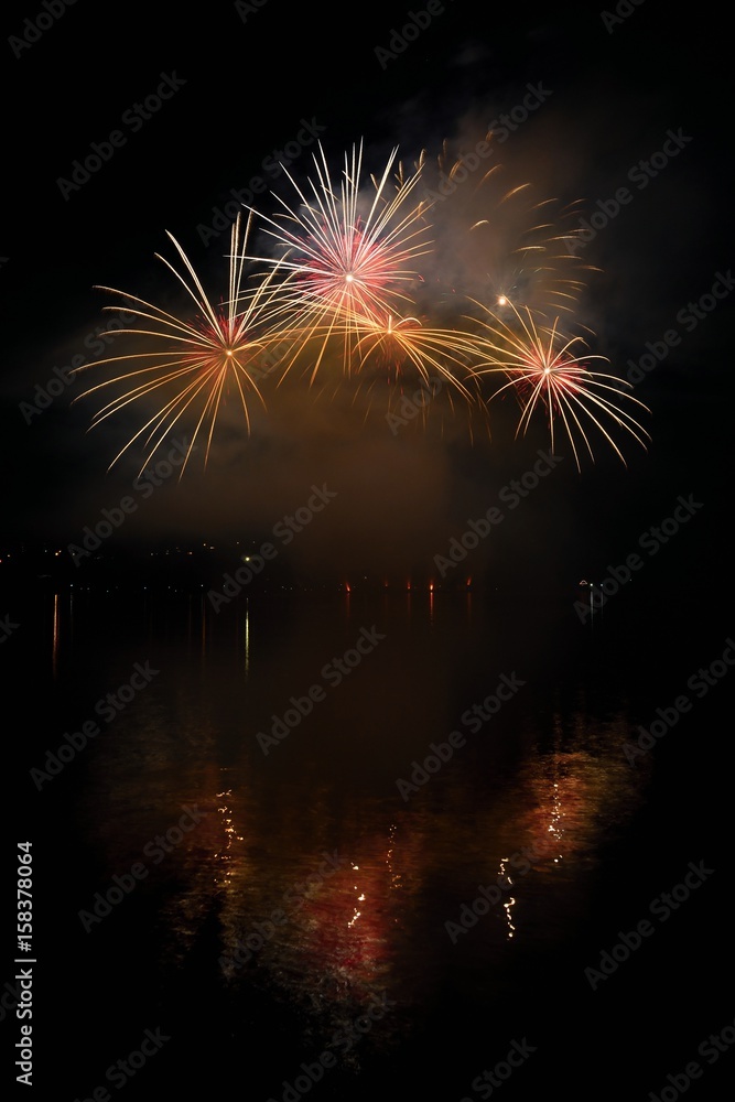 Beautiful colorful fireworks on the water surface with a clean black ...