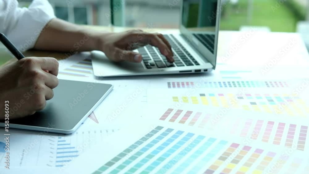 young male graphic designer working with computer and color swatch ...