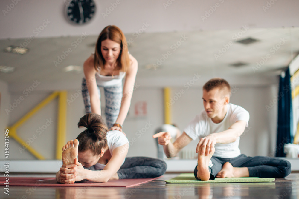 Yoga instructor helps beginner to make Stretching exercises. Teacher ...