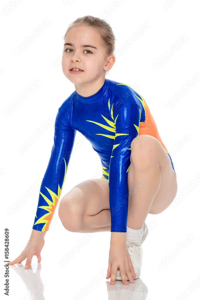 Beautiful little girl gymnast is squatting. Stock Photo | Adobe Stock