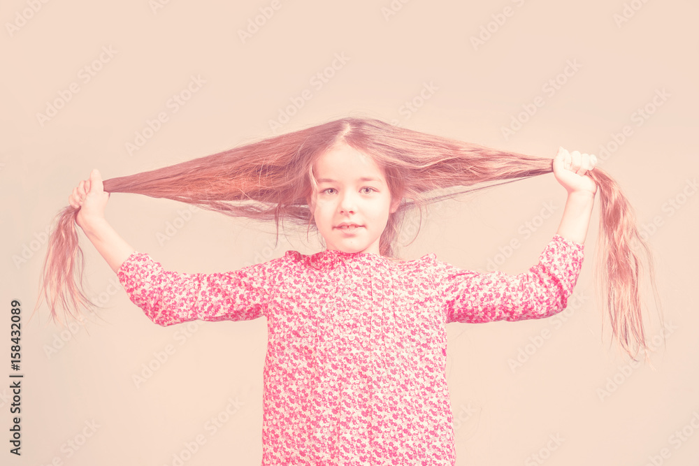 Cute little girl in a red dress pulling long hair in different ...