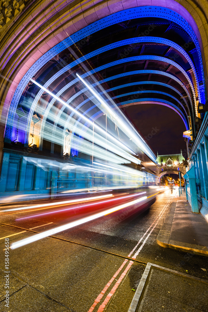 Tower Bridge at night with light trails of a red double-decker bus ...