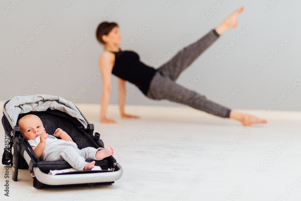 Little baby lying in child pram while his mother workout on the ...