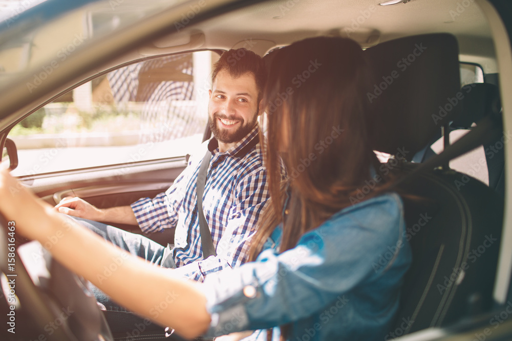 Careful driving. Beautiful young couple sitting on the front passenger ...