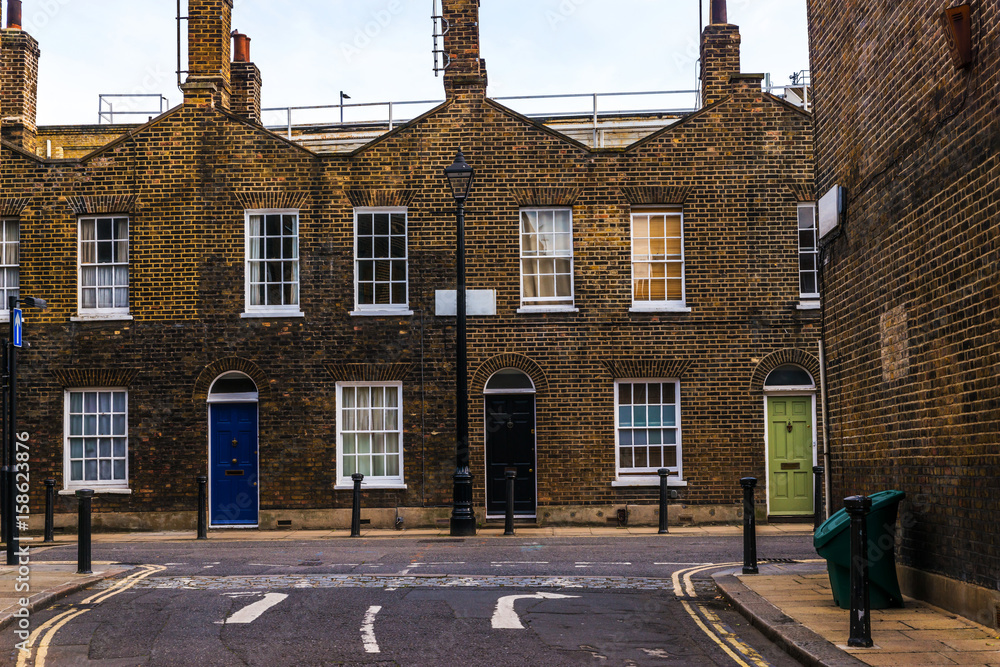 Typical old English buildings, low brick buildings across a narrow ...