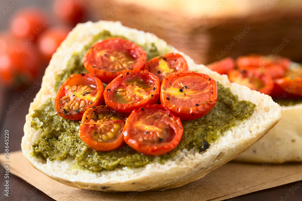 Olive bread roll halves spread with basil pesto and topped with roasted ...