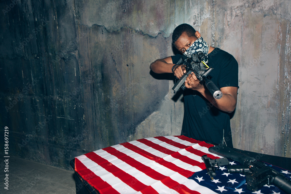 Black soldier checks his weapon. Mercenary man with rifle in hand on ...