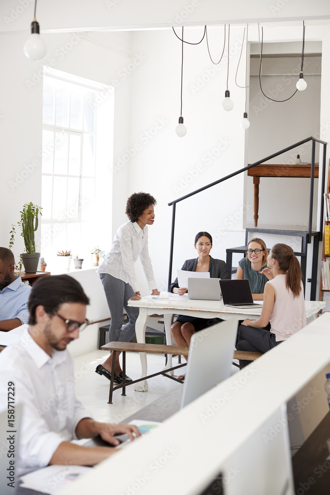 Woman briefing colleagues in an open plan office, vertical Stock Photo ...