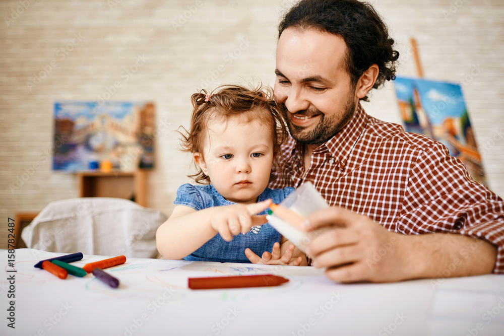 Portrait of smiling man with cute baby girl drawing in art class using ...