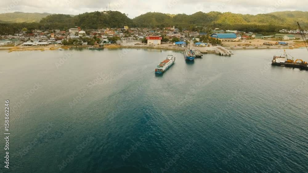 Cargo and passenger port with barges and cargo ships on tropical island ...