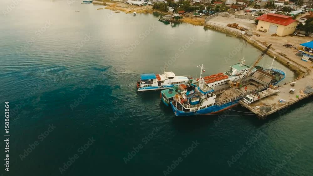 Cargo and passenger port with barges and cargo ships on tropical island ...
