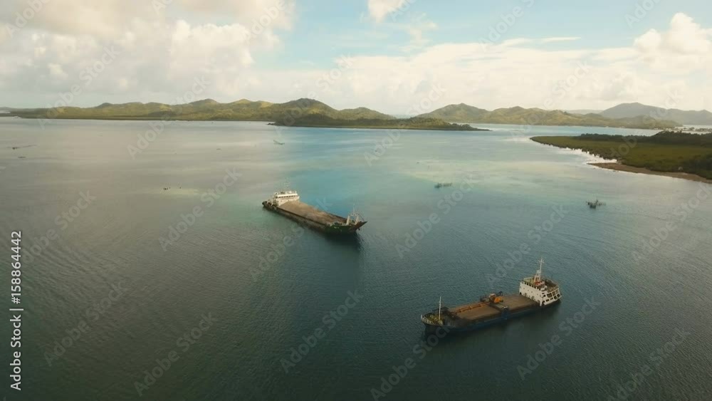 Cargo and passenger port with barges and cargo ships on tropical island ...