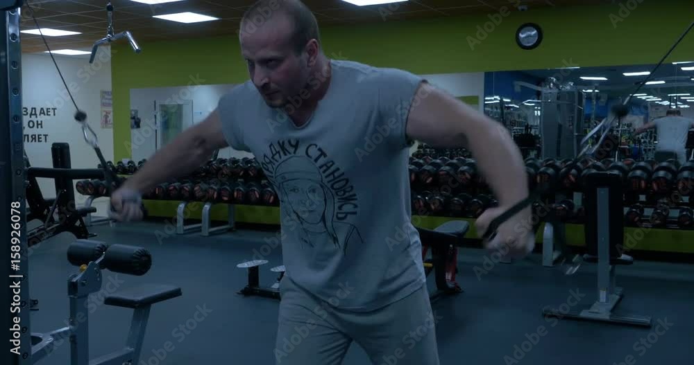 Bodybuilder doing butterfly on cable pull for better definition of his ...