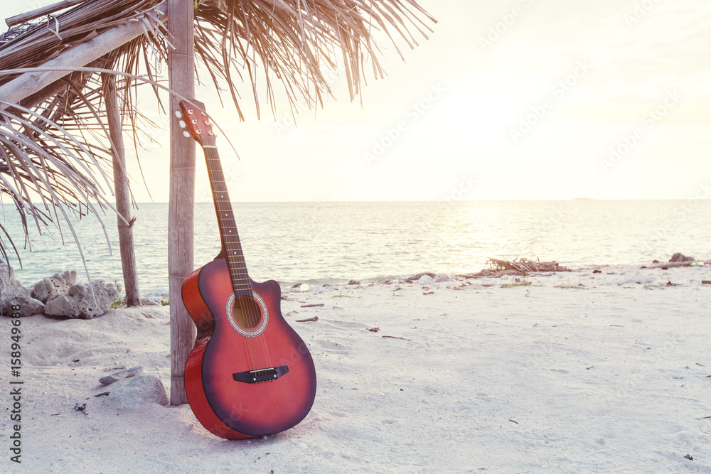An acoustic guitar standing in the sandy beach under palm tree Stock ...