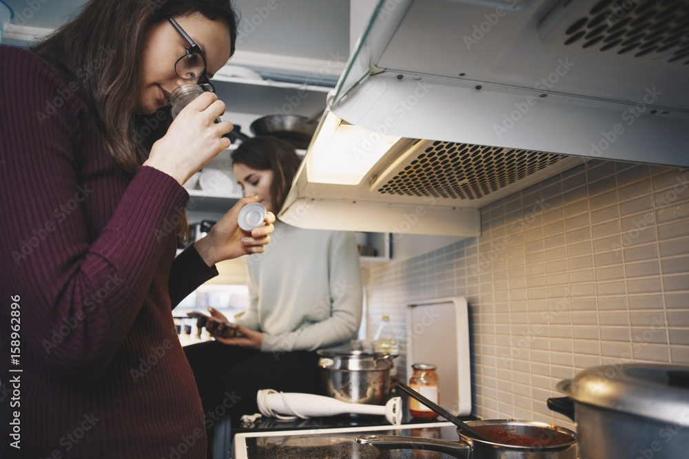 Woman smelling ingredient in bottle while cooking food Stock Photo ...