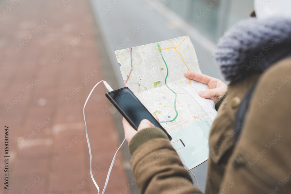 Over shoulder view of female backpacker with smartphone looking at map ...