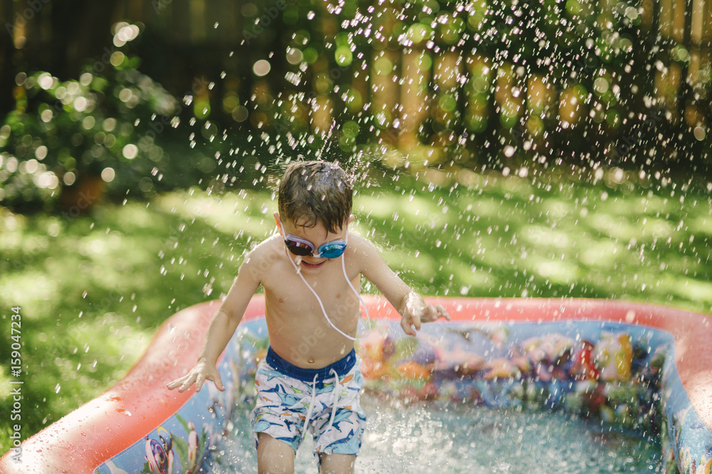 Young boy playing in kiddie pool in the backyard Stock Photo | Adobe Stock