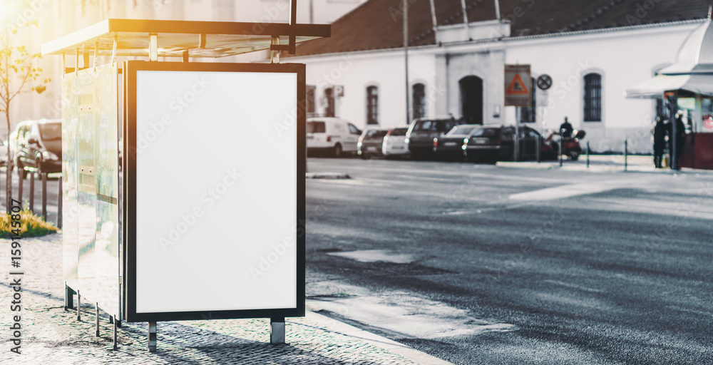 City bus stop on paving stone with empty poster, blank vertical ...