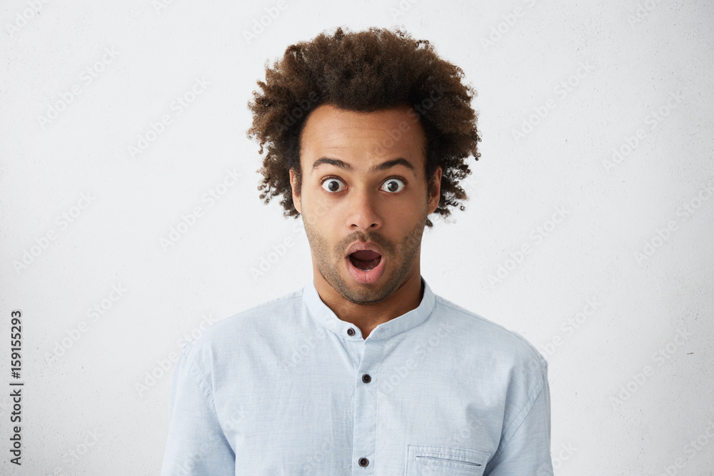 Studio portrait of bug-eyed dark-skinned man with bushy dark hair and ...