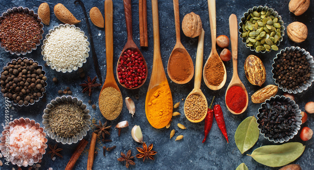 Various indian spices in wooden spoons and metal bowls, herbs and nuts ...