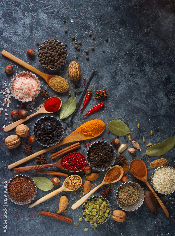 Various indian spices in wooden spoons and metal bowls, herbs and nuts ...