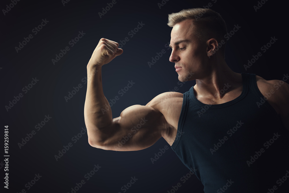 Young confindent muscular bodybuilder guy standing on black background ...