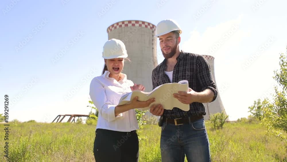 Two happy successful engineers with blueprints in hands on the ...