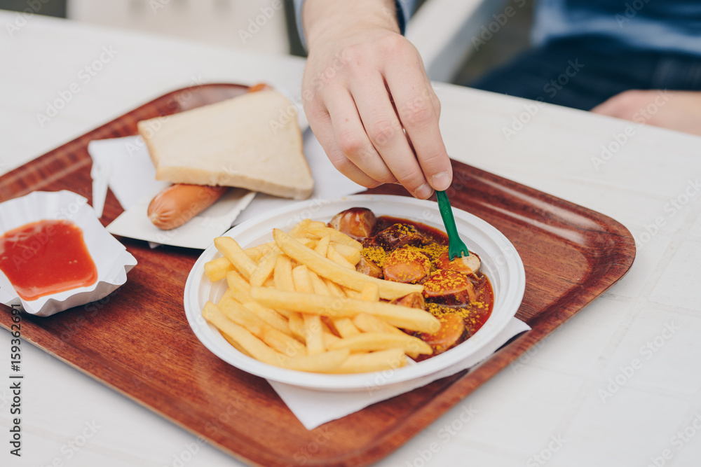 hands of a man eating a currywurst with a fries outdoor Stock-Foto ...