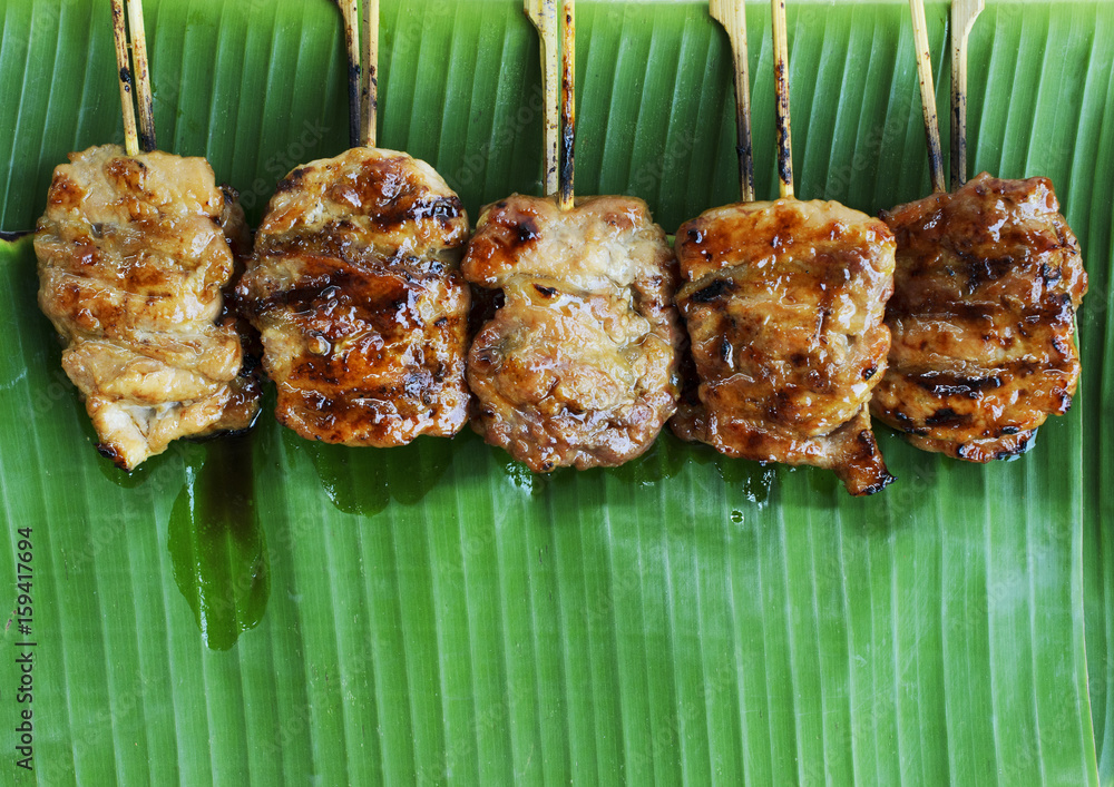 Grilled pork or mooping thai local street food on banana green leaf ...