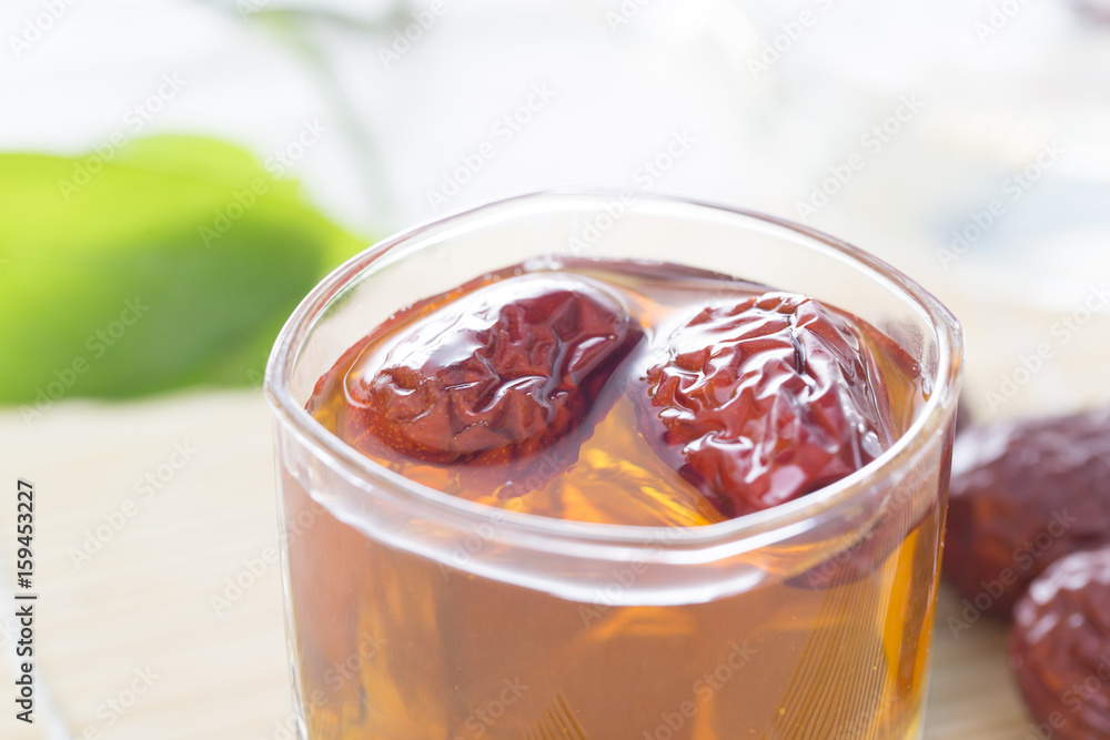 A glass cup of Chinese red date tea on the table. Chinese red dates are ...