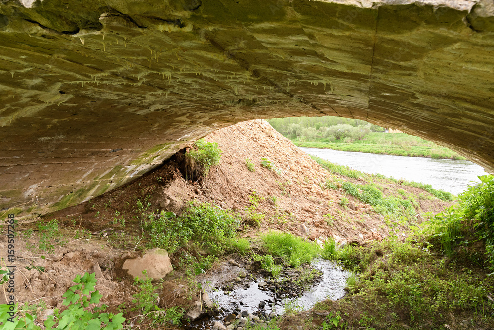 The Creek flowing under the bridge with stalactites of limestone to the ...