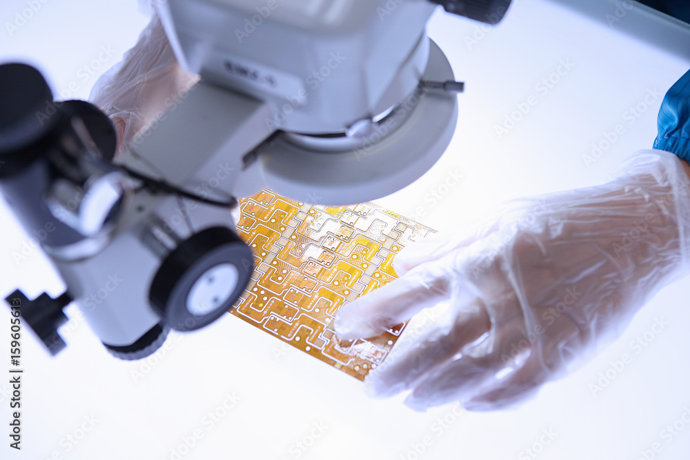 Hand of female worker using microscope to examine flex circuit in ...