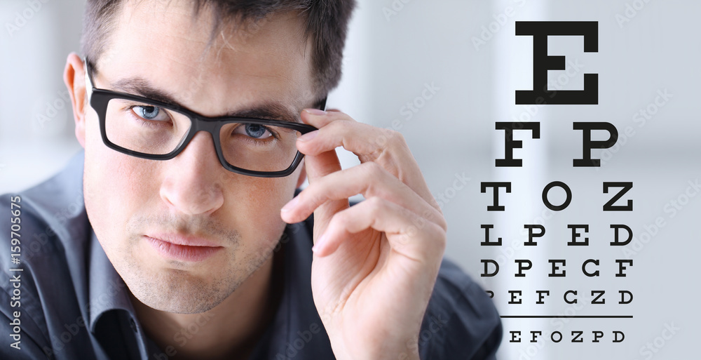 male face with spectacles on eyesight test chart background, eye ...