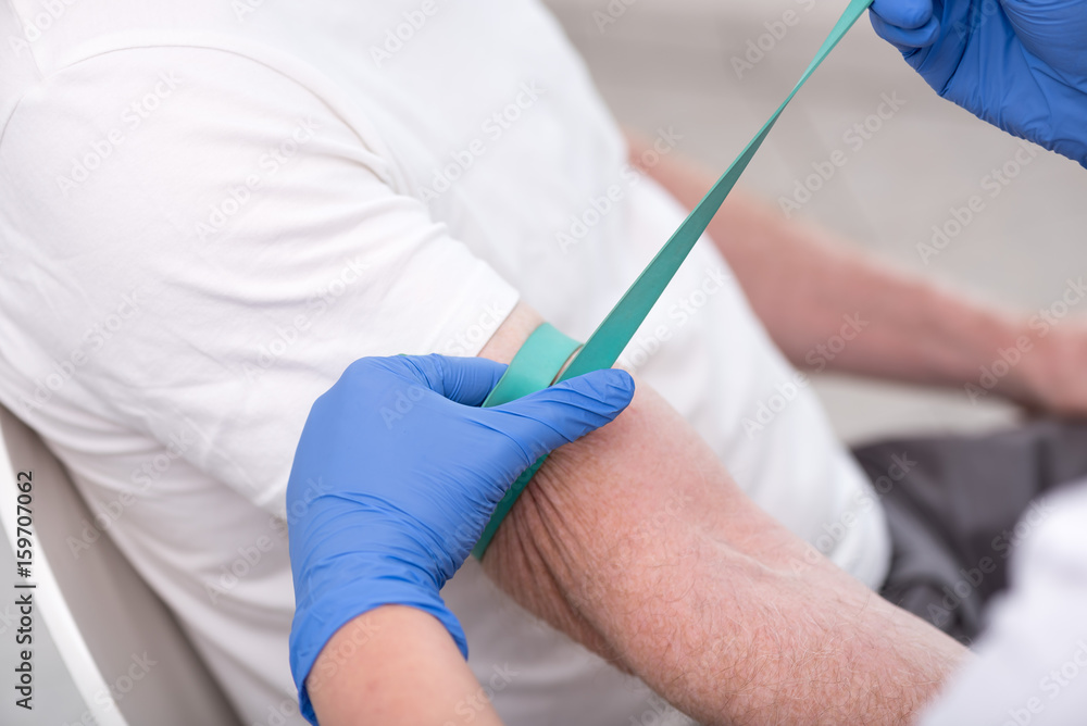 Putting a tourniquet on the arm of a patient Stock Photo | Adobe Stock