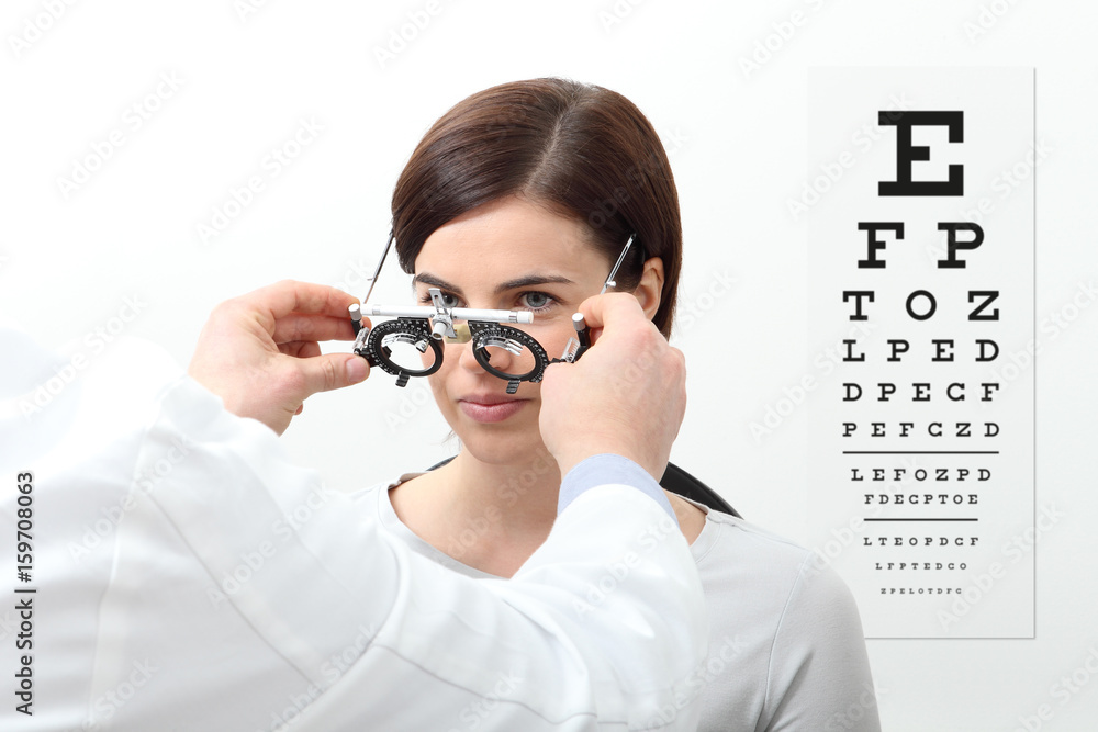 woman doing eyesight measurement with trial frame and visual test chart ...