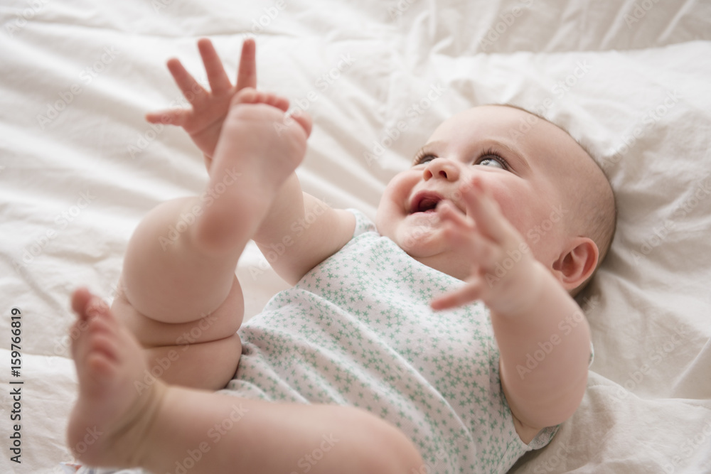 Baby girl lying down with arms and legs up Stock Photo | Adobe Stock