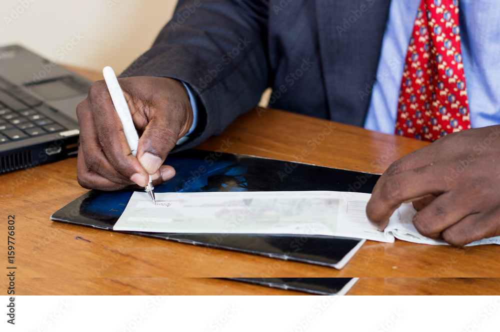Signing a check in his office. Stock Photo | Adobe Stock