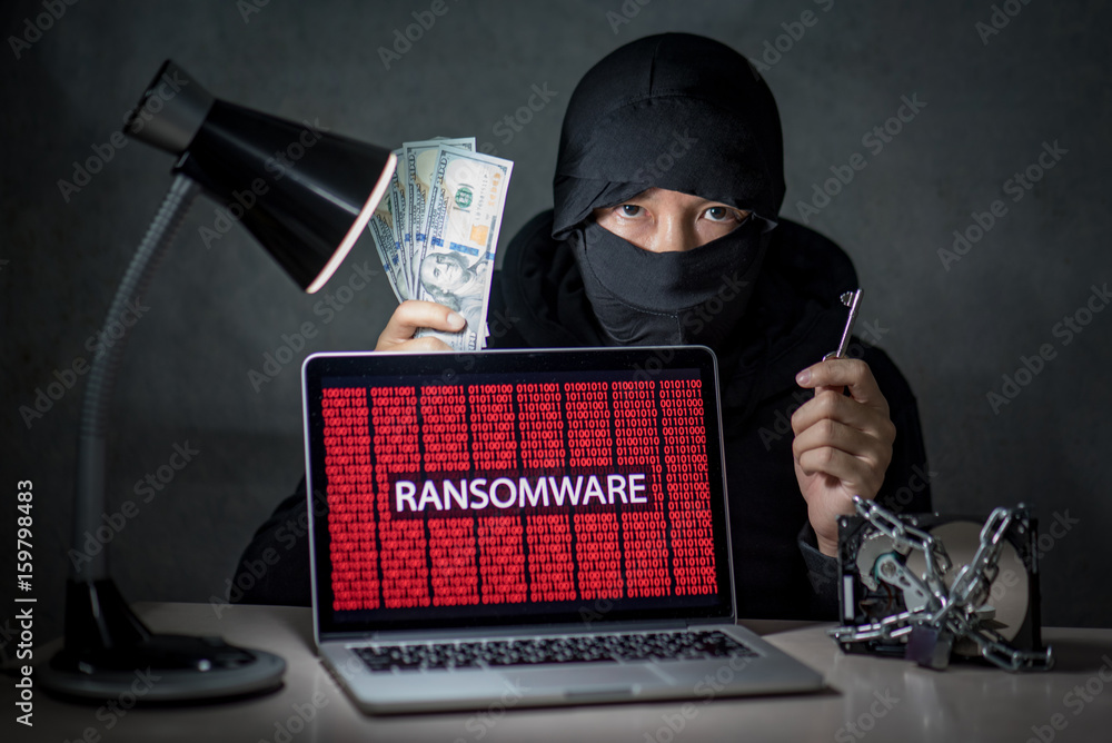 Hacker holding key and money with laptop computer screen showing ransomware attacking, alert in ...