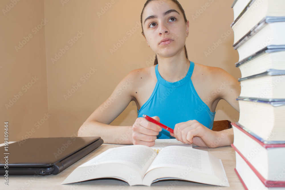 Girl doing her homework. books on the desk in the auditorium. Girl ...
