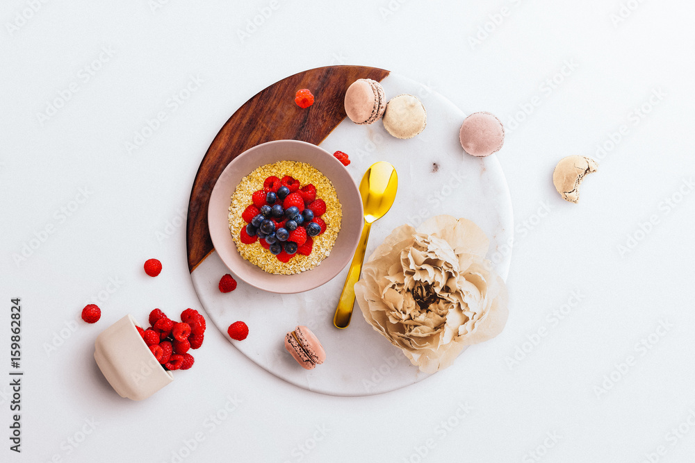 Breakfast flatlay scene, with fresh fruit, oats, macaroons, a peony and ...