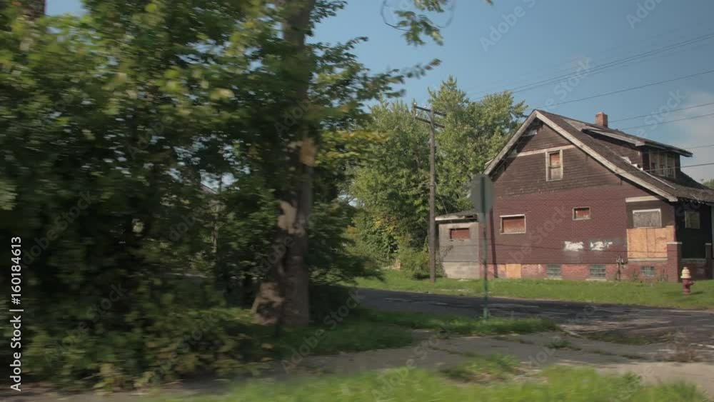 CLOSE UP: Driving along bad cracked street past abandoned ruined home ...