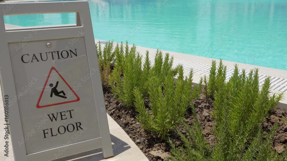 Caution wet floor sign on outdoor swimming pool. Open air poolside with ...